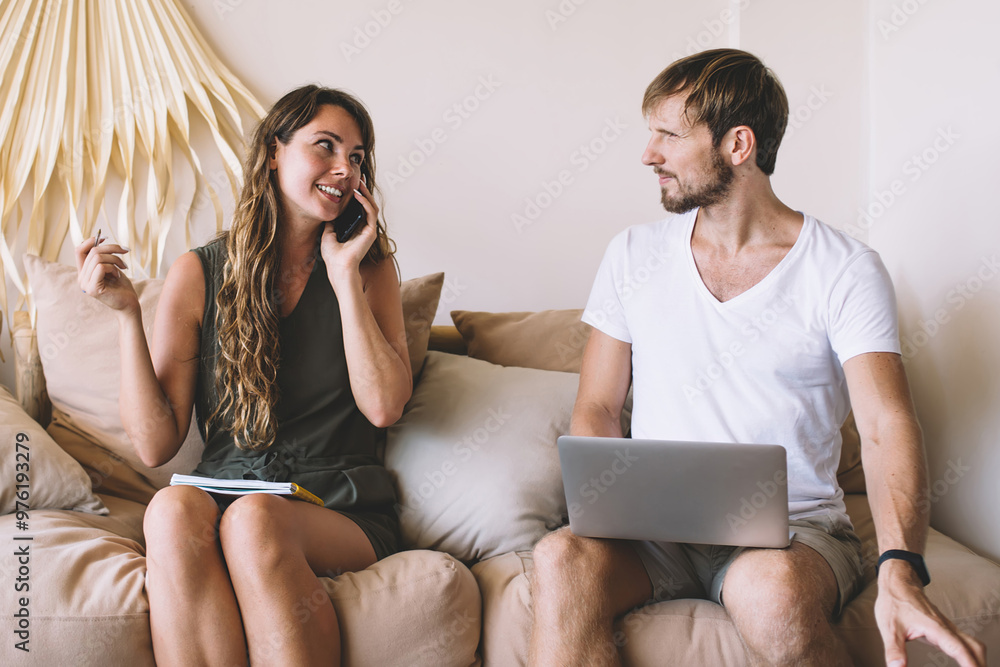 Positive male and female sitting on sofa and discussing information ...