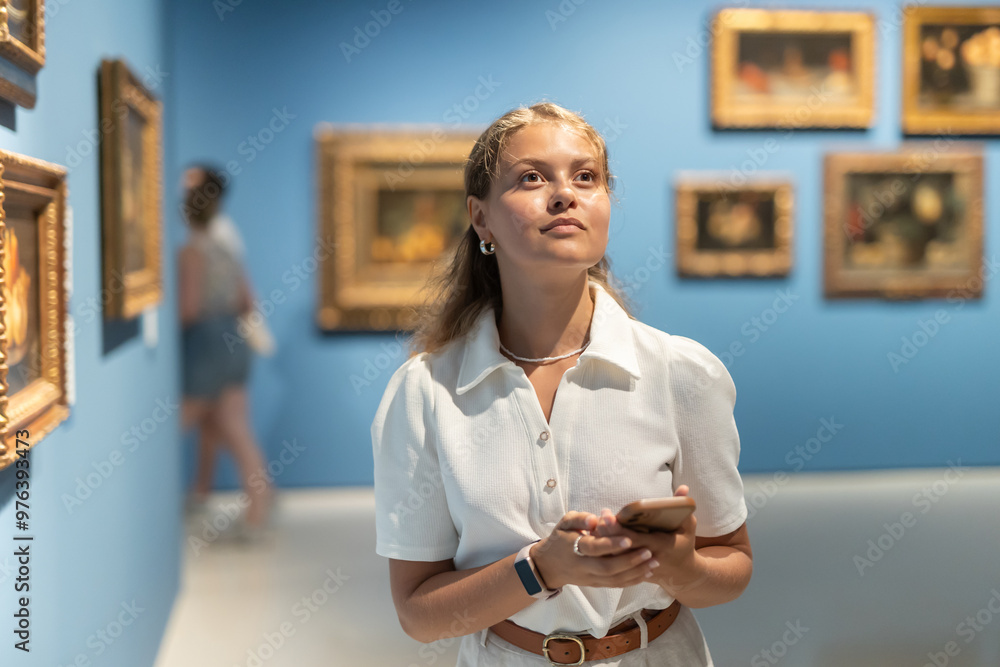 Museum female visitor with phone in hands walk through exhibition halls ...