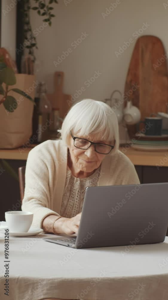 Vertical shot of elderly lady surfing internet on laptop while sitting ...
