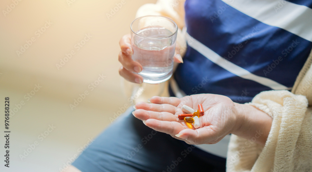 Old woman hand holds red medication capsules of omega 3, vitamin D and ...