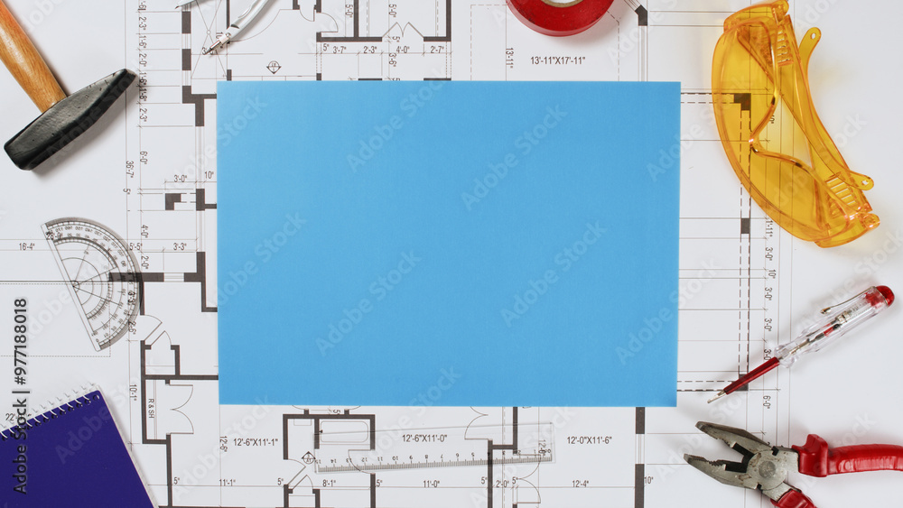 A paper model of a house plan with tools and a notebook on it, with ...