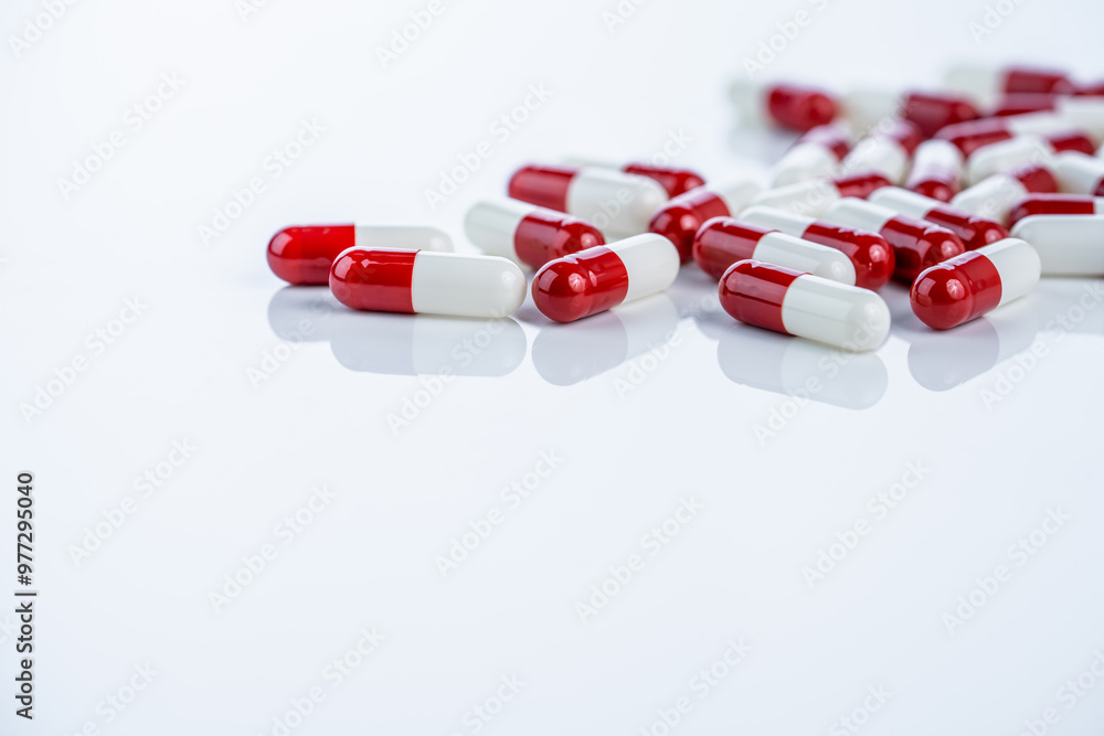 Red white capsules scattered on white background illustrate drug ...