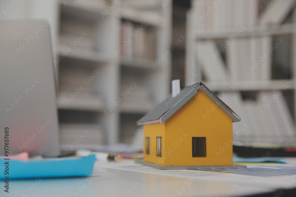 Wooden table with laptop, house keys Clipboard with pen, house model ...