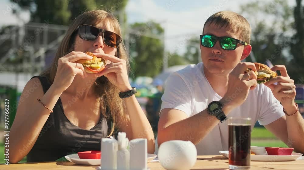 Man and woman snacking on delicious burgers looking only at each other ...