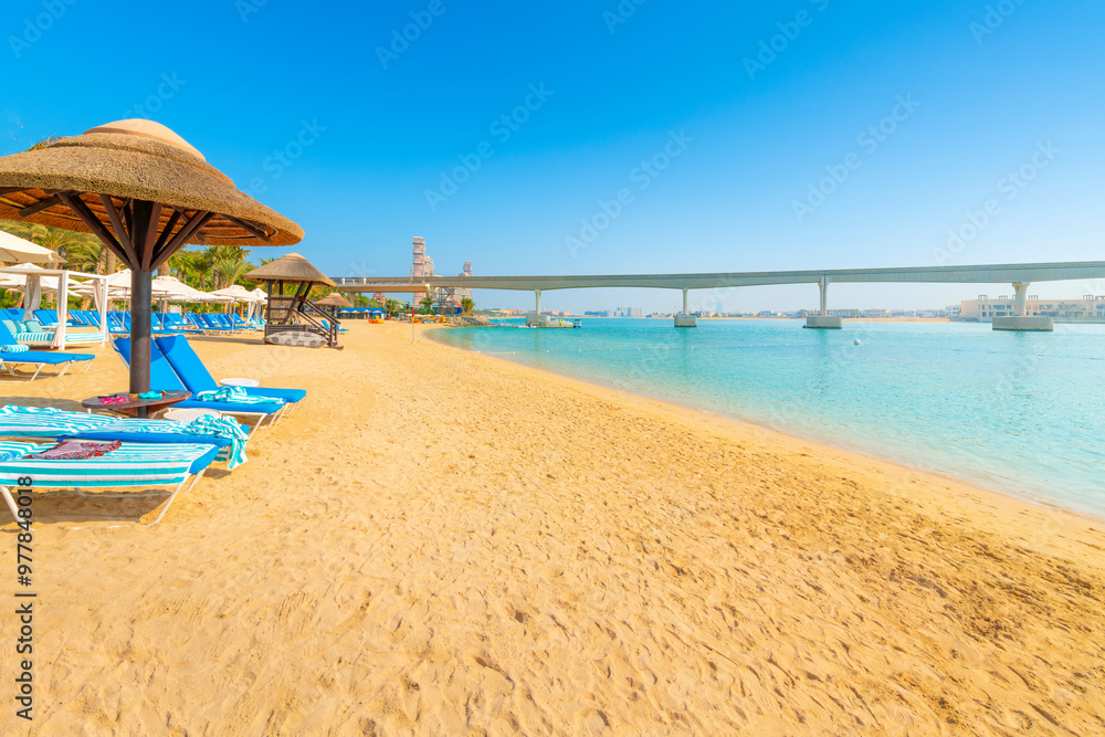 Lounge chairs, palm trees and huts along a sandy beach on the Arabian ...