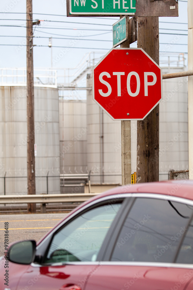Red car stopped at a stop sign, and a cement and concrete big ...