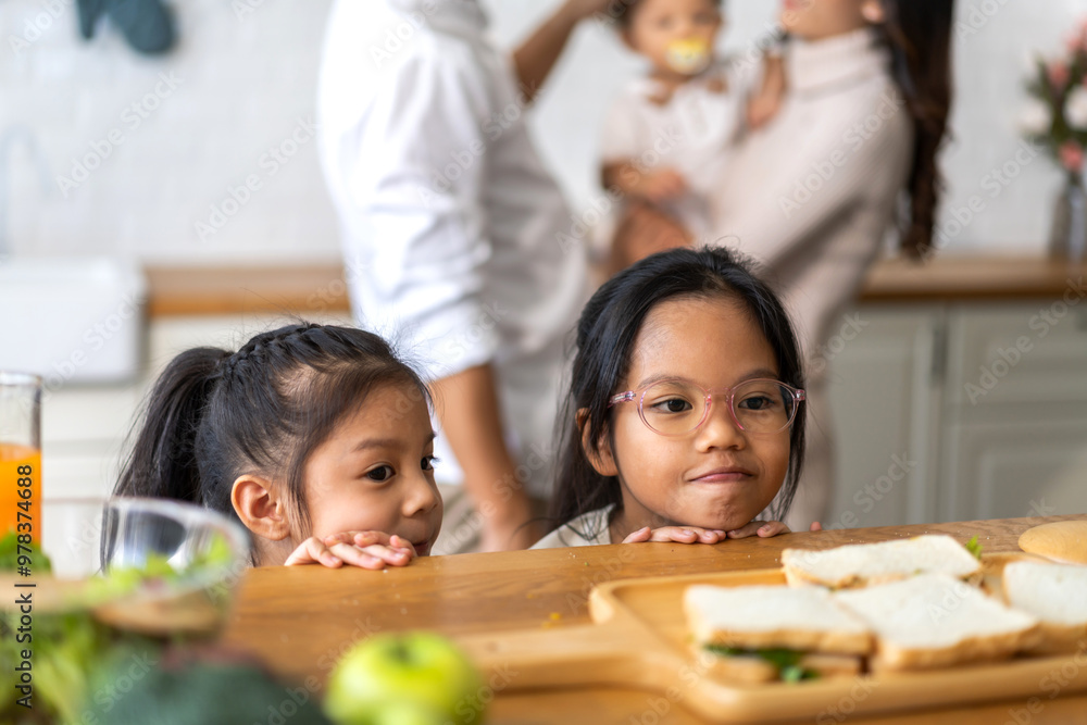 Two curious little girls look at homemade sandwiches on kitchen counter ...