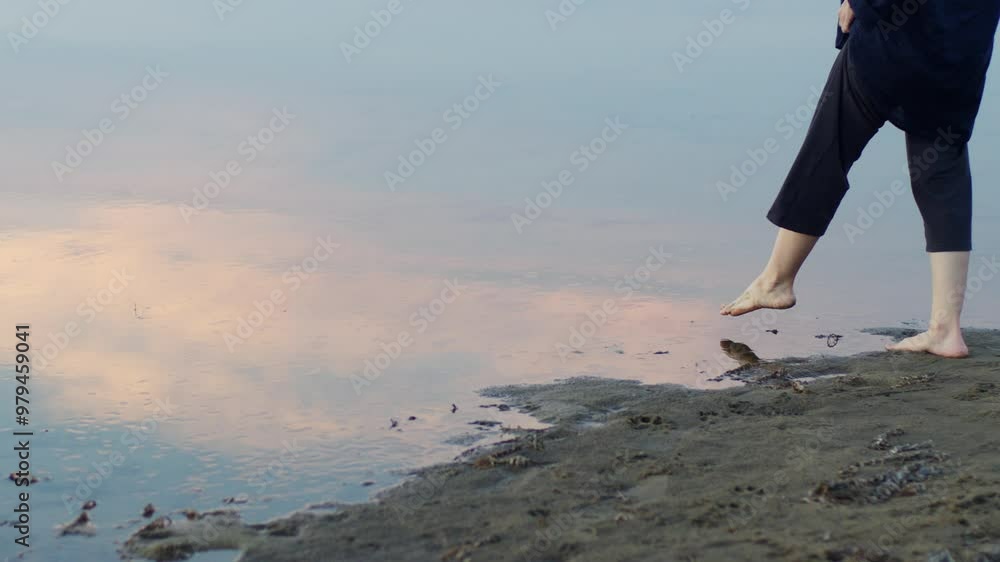 Steps of a woman's feet entering the water with the reflection of the ...