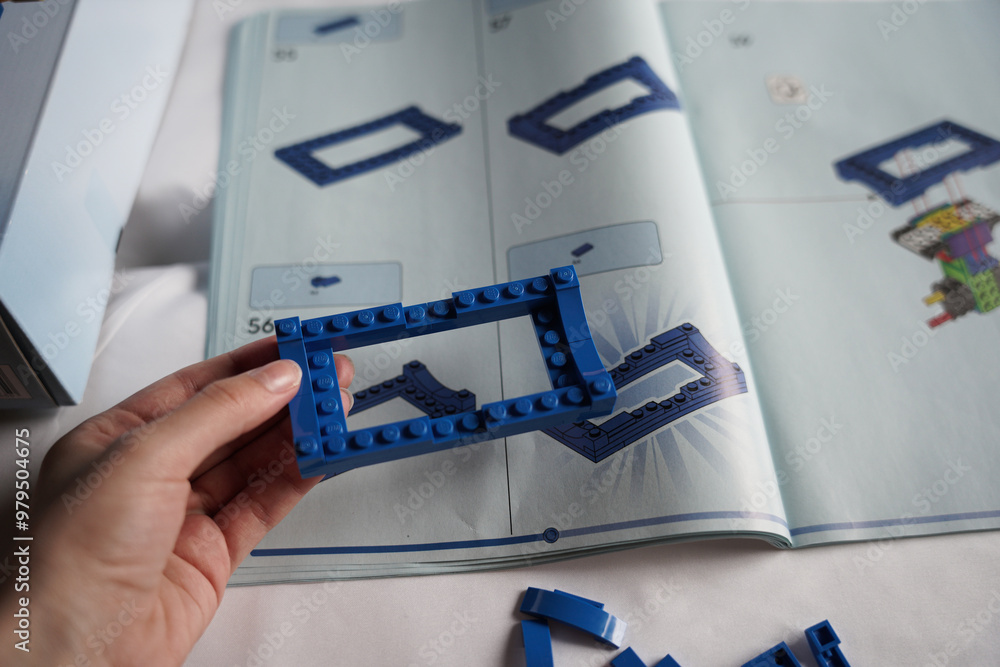 A lady's hand builds the up-scaled LEGO® Minifigure on a white table ...