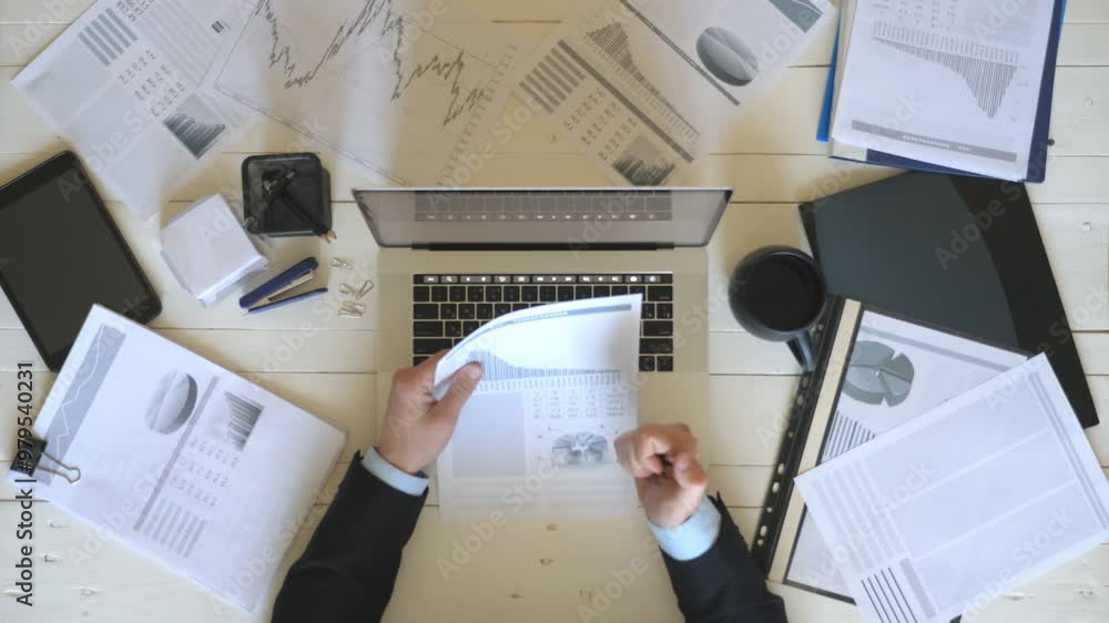 Top view hands of young businessman looking at diagrams with statistic ...