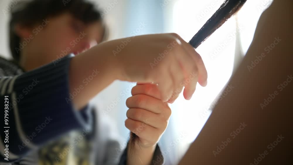 Young boy grasping his mother's hair with both hands, a subtle ...