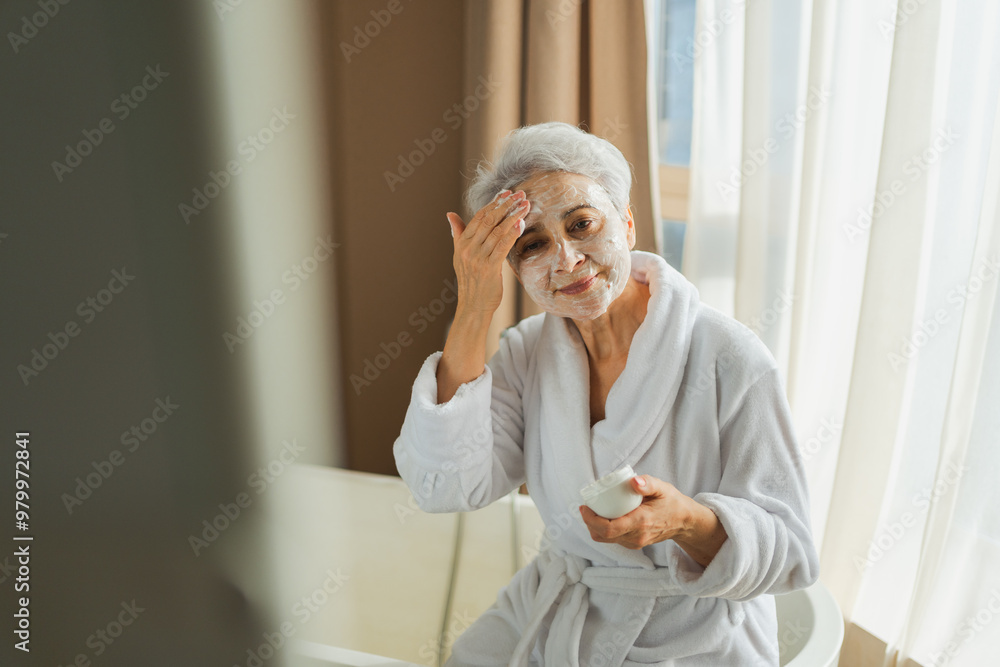 Mature adult old woman applying nourishing anti age face cream doing ...