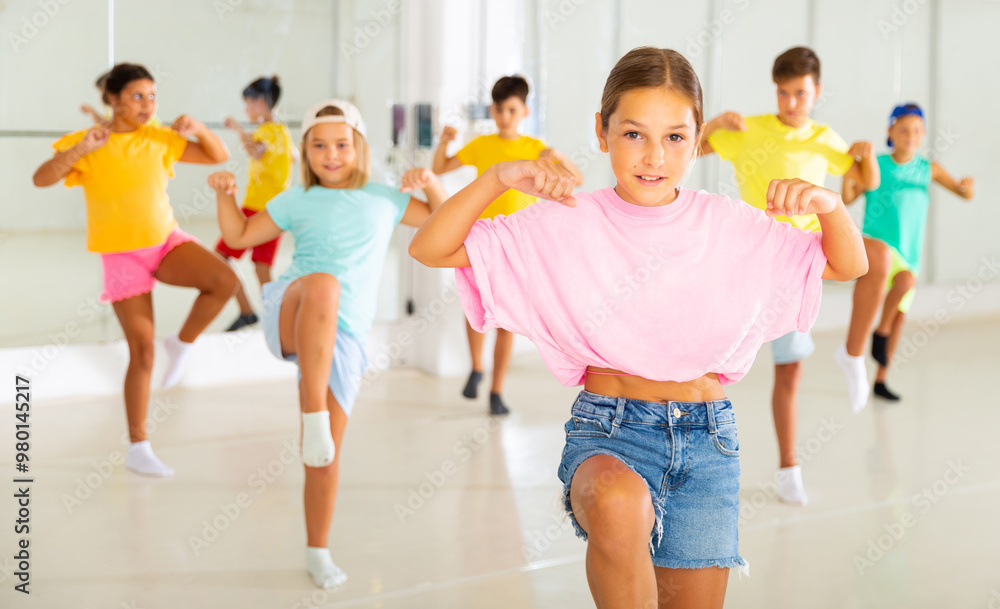 Confident tween girl breakdancer posing during workout in group dance ...
