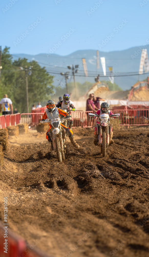 Motocross riders racing on a muddy track during an outdoor mountain ...