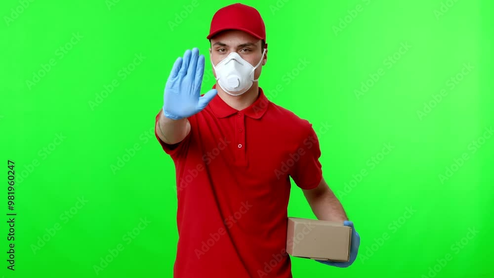 A delivery worker dressed in a red uniform, gloves, and a mask is ...