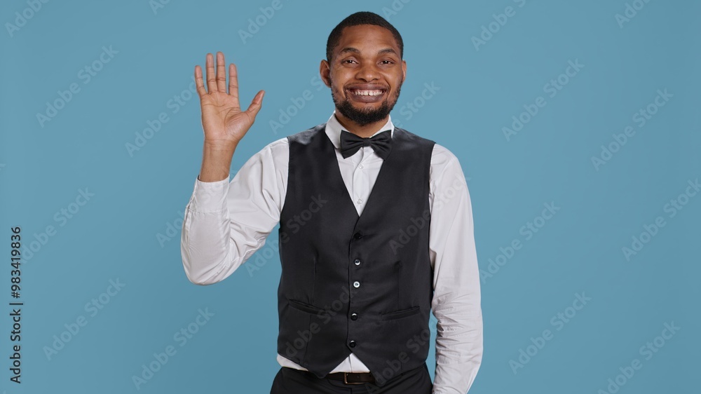 Bellboy employee smiling and waving hello at hotel guests, greeting ...