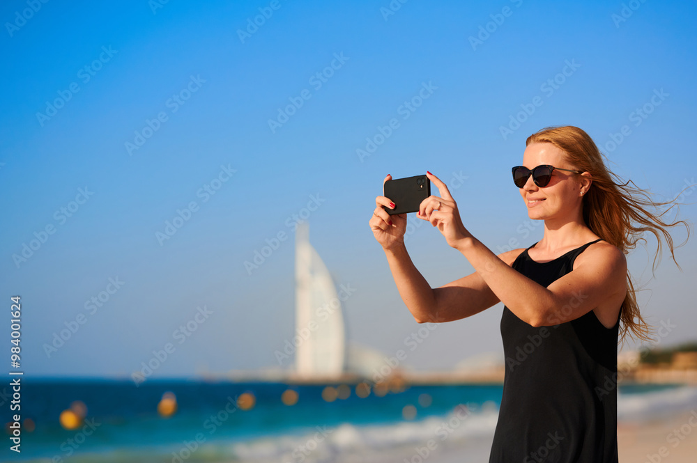 Stylish traveler on vacation at the beach snaps a photo with her ...
