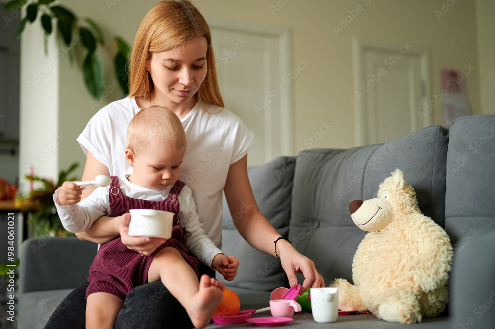 Young mother and baby role play with a teddy bear, baby plastic ...