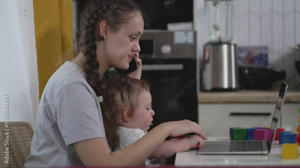 Mom work on laptop with baby. Baby chewing toy while mother types. home ...
