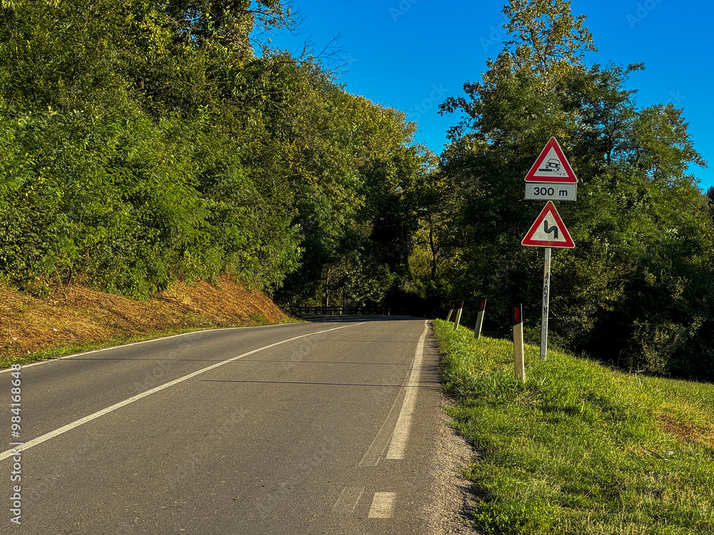 A quiet country road with warning signs indicating sharp turns ahead ... A quiet country road with warning signs indicating sharp turns ahead ...