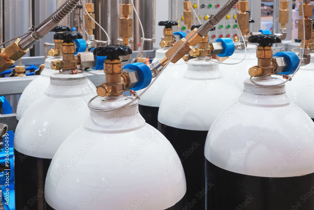 A row of white and black cylinders of compressed gas. The cylinders are ...