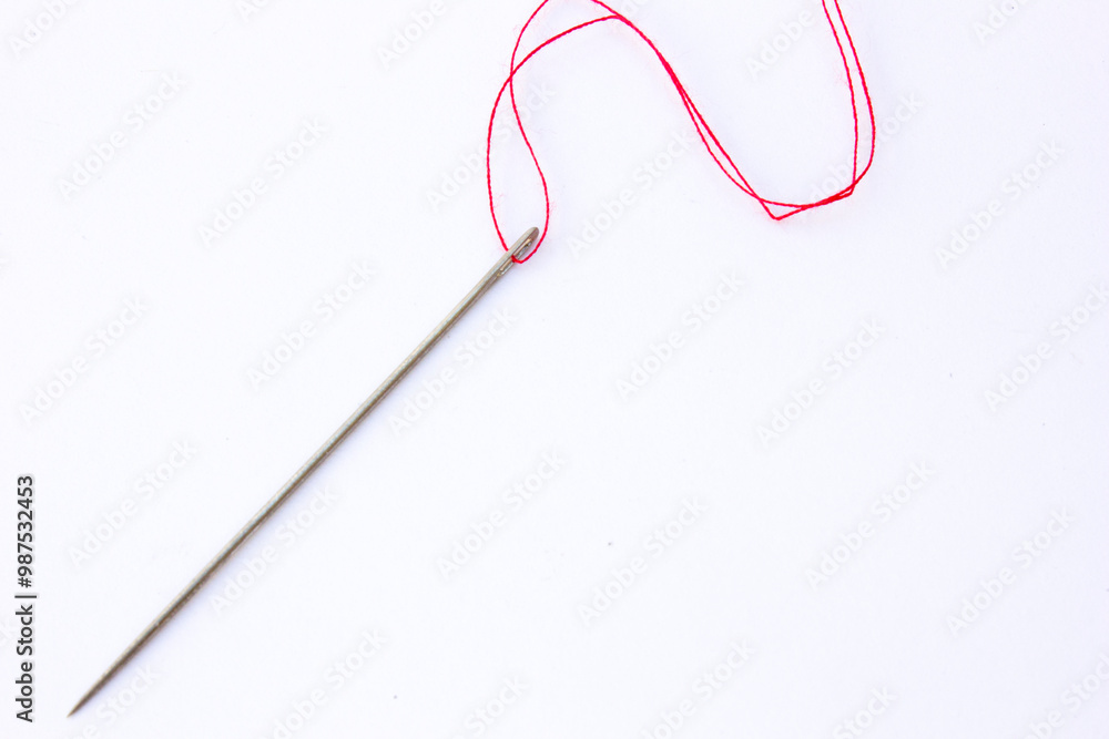 This clean and simple image showcases a sewing needle placed on a white ...