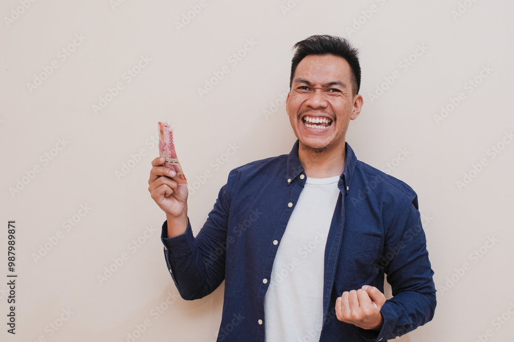 Excited a Southeast Asian man in a casual dress holding cash money and ...