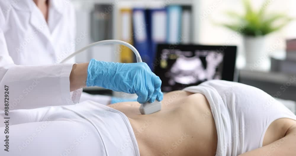 Doctor uses ultrasound machine examining female patient abdomen in ...
