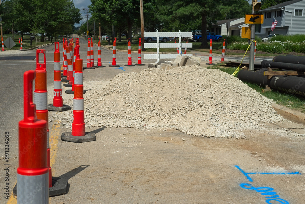 Traffic cones, a gravel pile, and pipe sections mark the start of a ...