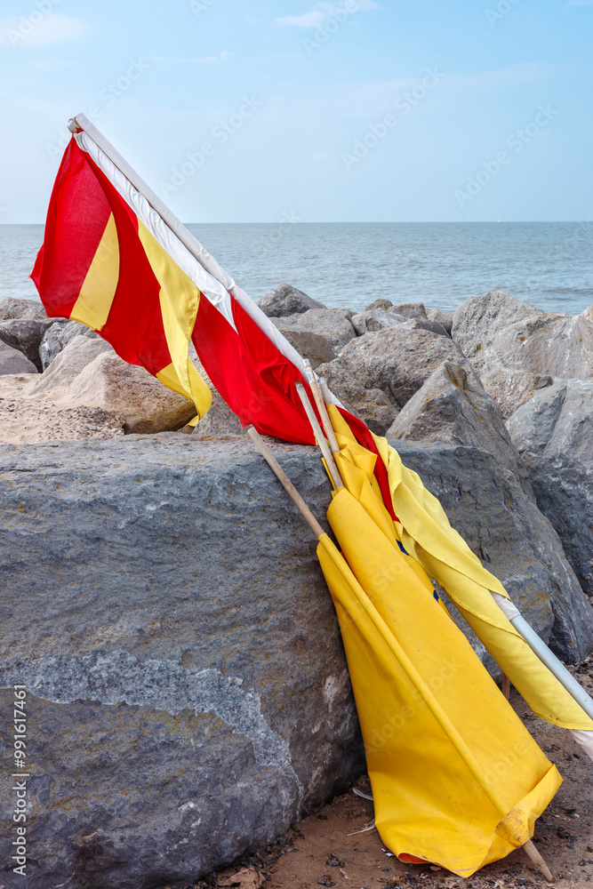 Beach caution flags signal safe swimming zones by the rocky shoreline ...