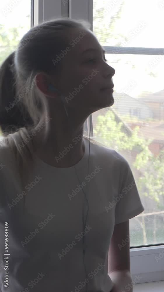 Vertical, An adolescent dances by the window at home, lost in the ...
