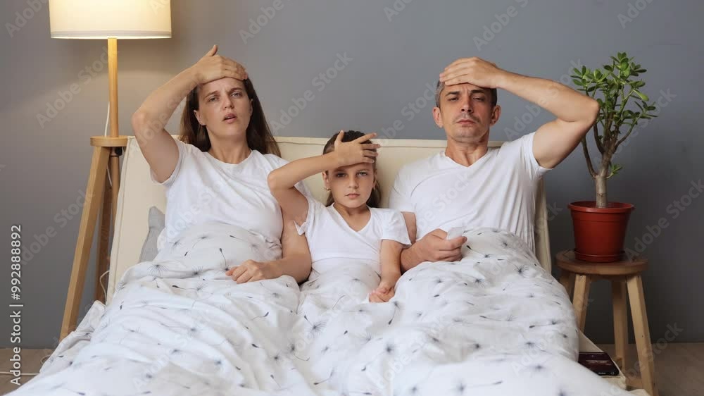 Sick little girl lying in bed with her parents family suffering painful ...