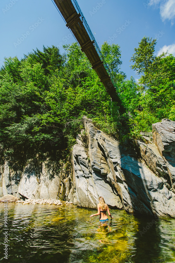 Blonde woman in bikini swimming and relaxing in a clear water river ...