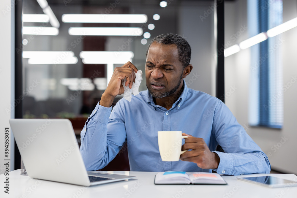 Office worker feeling unwell at desk, showing signs of illness. Holding ...