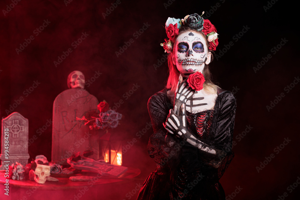 Woman posing with red rose in graveyard scene while wearing skeleton ...