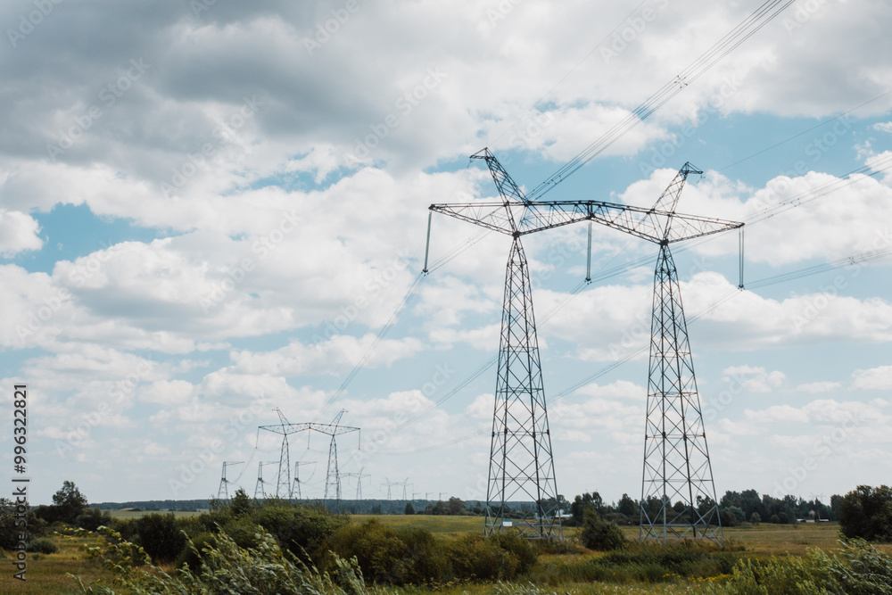 High voltage pylons against the blue sky with white clouds and bright ...