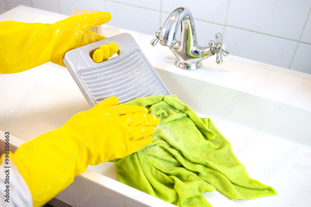 Hand washing clothes, removing dirt and stains, yellow rubber gloves ...