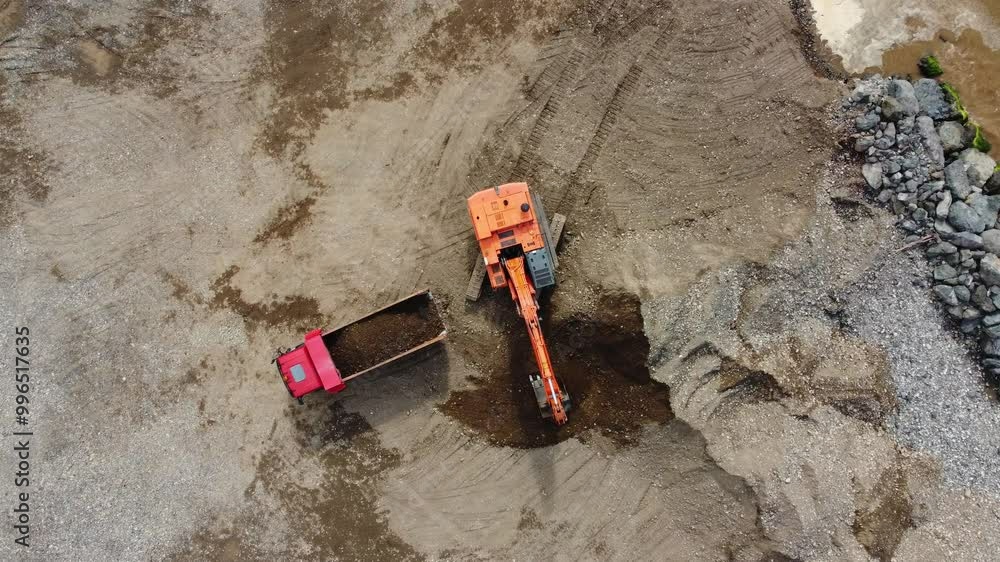 Excavator loading sand into dump truck at construction site near river ...