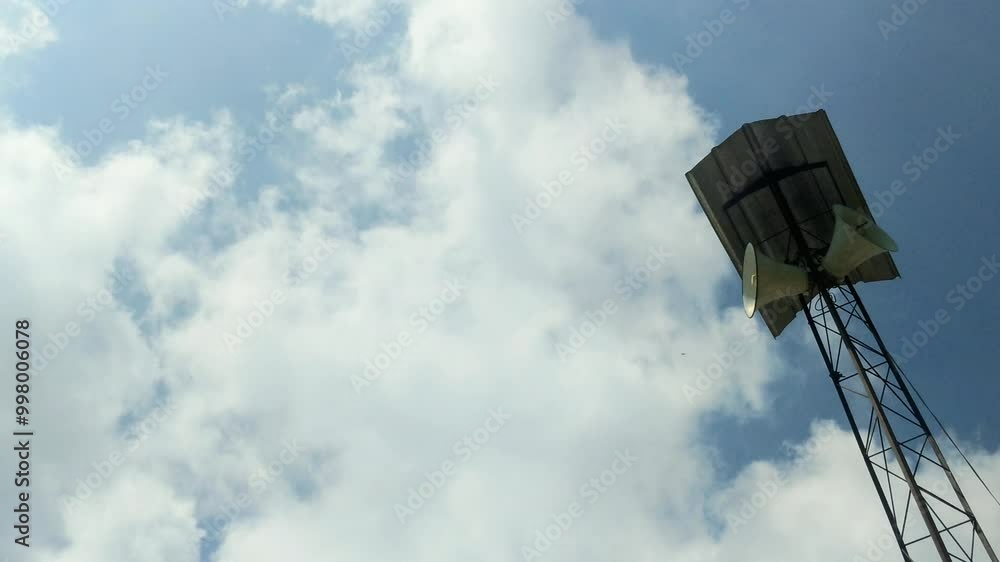 A tall communication tower with dual loudspeakers mounted under a metal ...