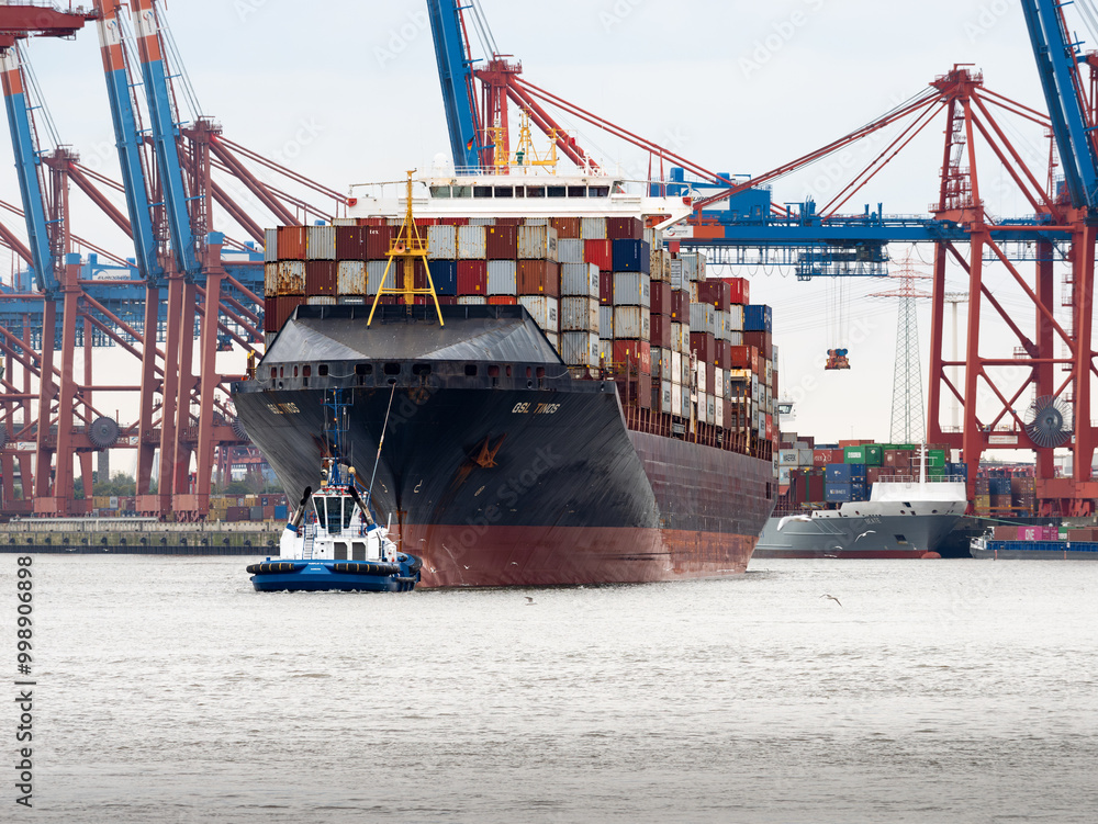HAMBURG, GERMANY - 9. September 2024: Tugboat pulling a huge container ...