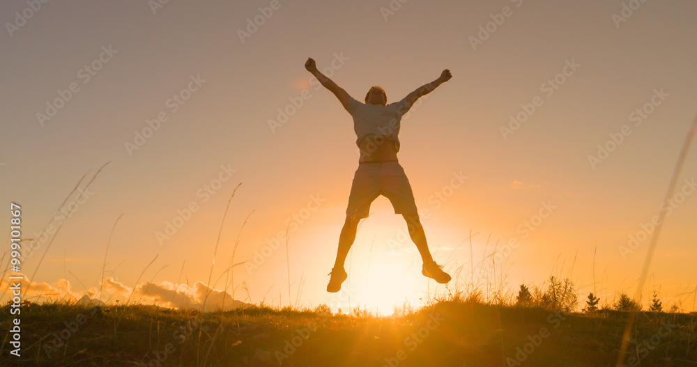 LOW ANGLE, LENS FLARE: Excited young man jumps in the air and ...