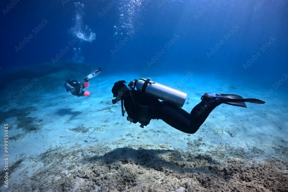 Pair of swimming scuba divers exploring rocky underwater seascape. Underwater photography from ...