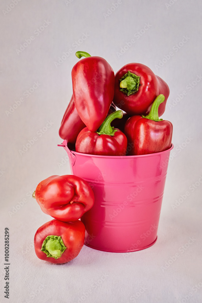 composition of paprika peppers in a pink bucket and two peppers below ...