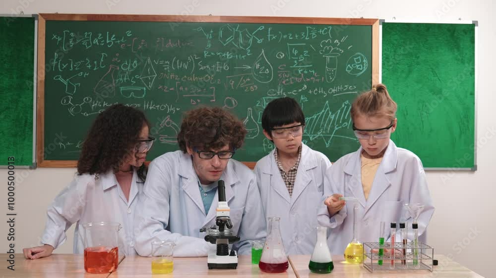 Smart caucasian teacher looking under microscope while diverse children ...