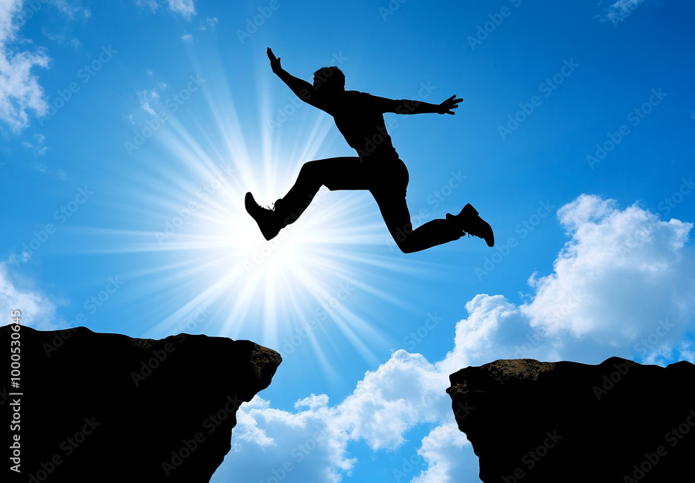 Silhouette of a man jumping over a chasm with a sun and blue sky ...