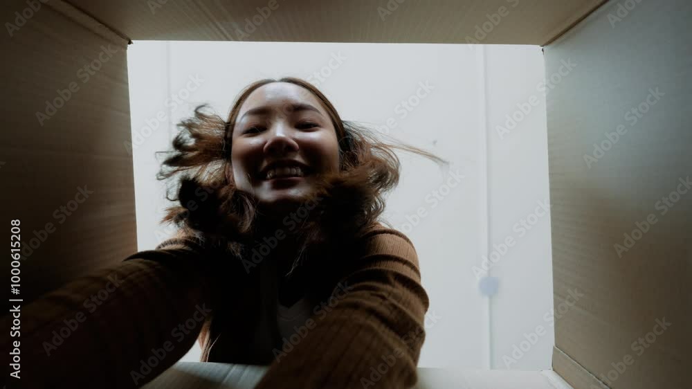 Low angle view of surprised young asian woman unpacking. Opening carton ...