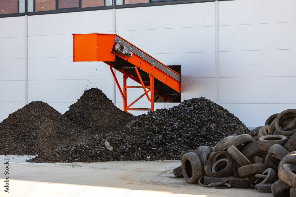 Tire recycling facility with shredded rubber piles and conveyor belt ...