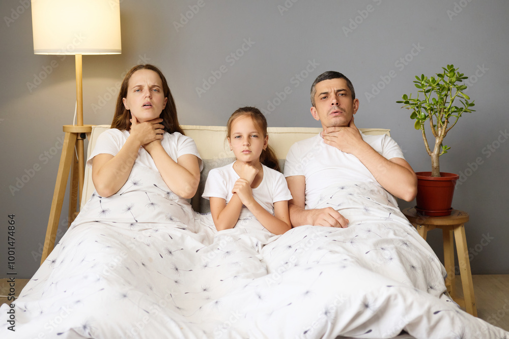 Sick father lying beside daughter and his wife with painful neck ache ...