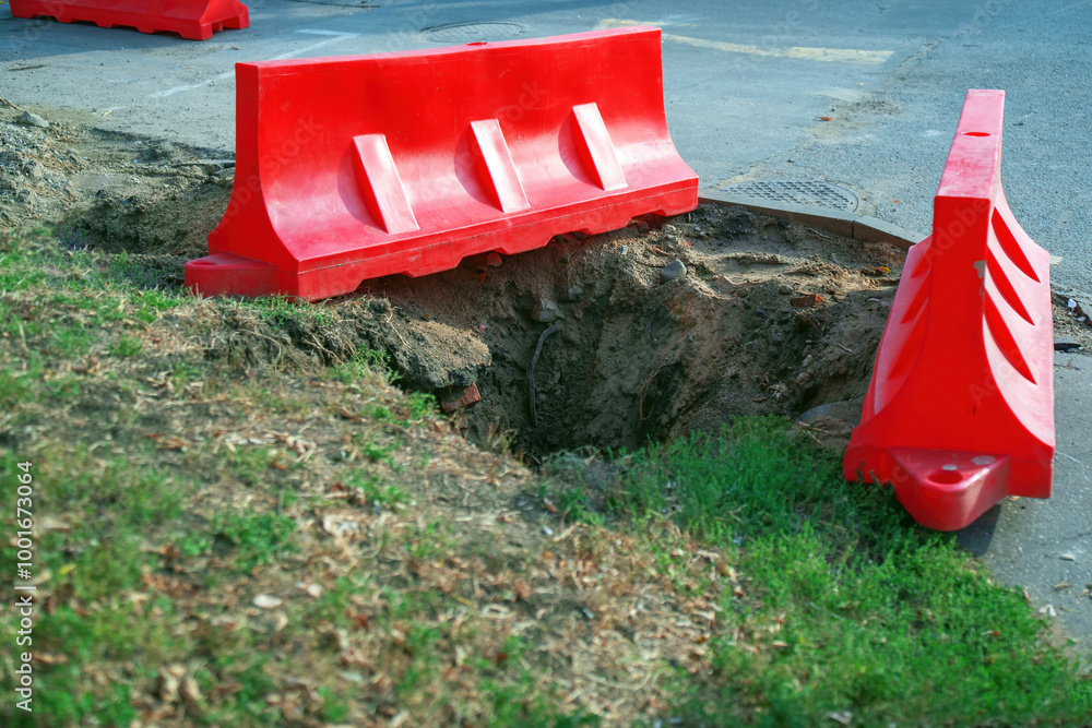 vibrant red plastic barrier surrounds a deep excavation for a well ...