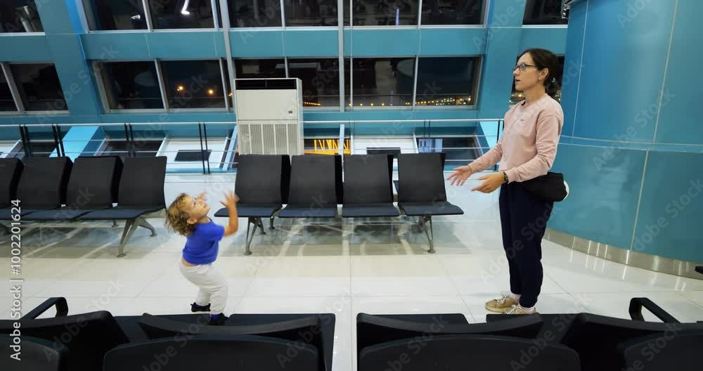 Mother and young son play with soft ball in empty airport terminal ...